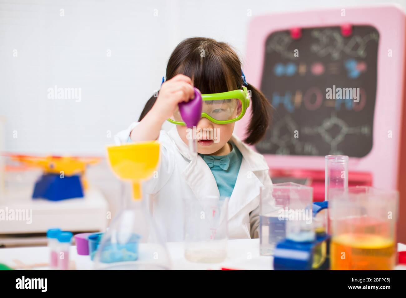 toddler girl pretend play scientist role at home against white ...