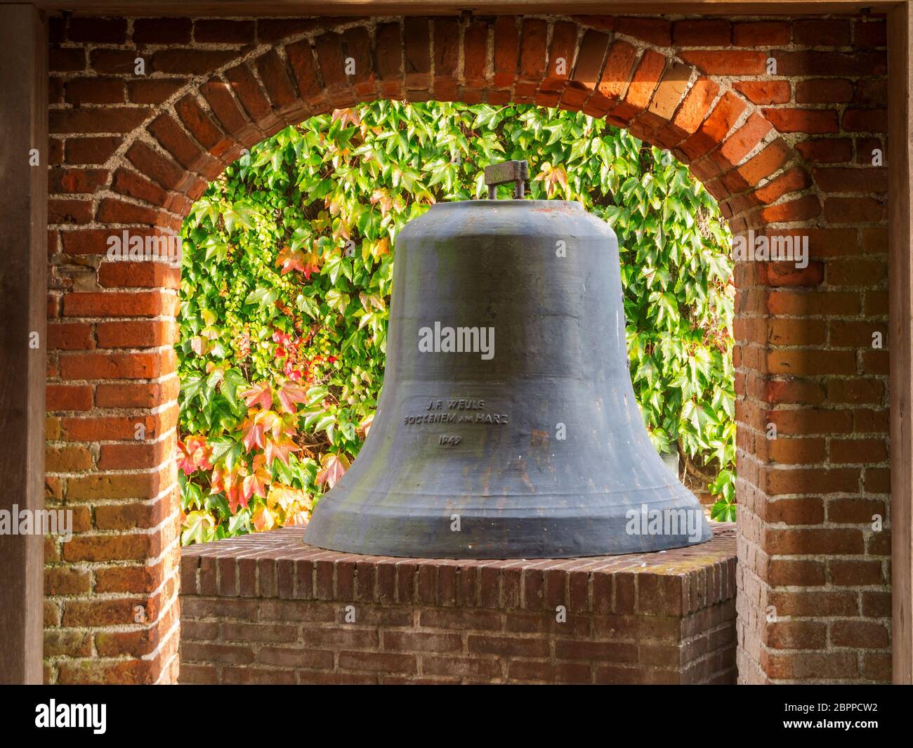 The bell in the cemetery in Carolinensiel framed by the brick arch of ...