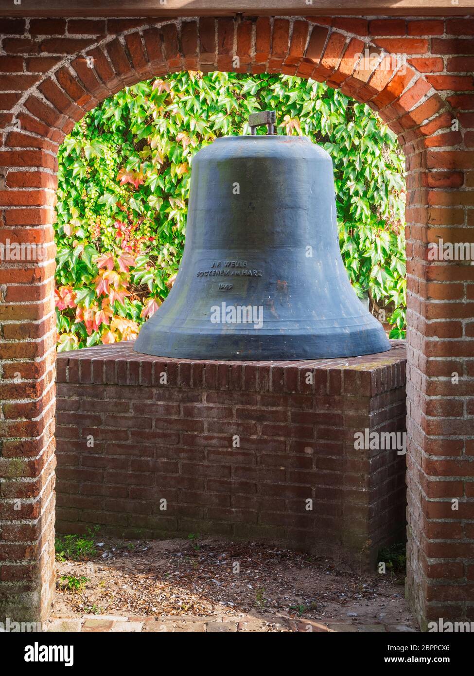 The bell in the cemetery in Carolinensiel framed by the brick arch of ...