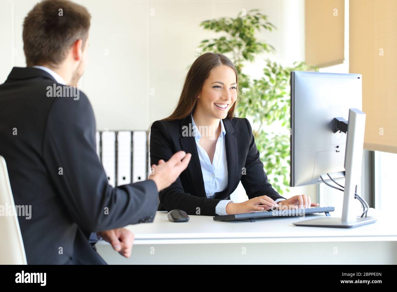 Agent attending to a client introducing data in a desktop computer at ...