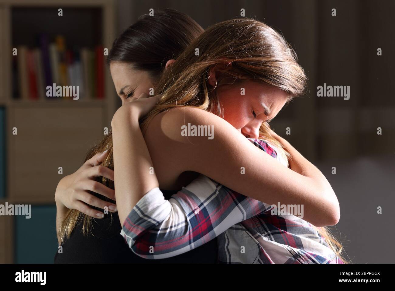 Side view of two sad good friends embracing in a bedroom in a house ...
