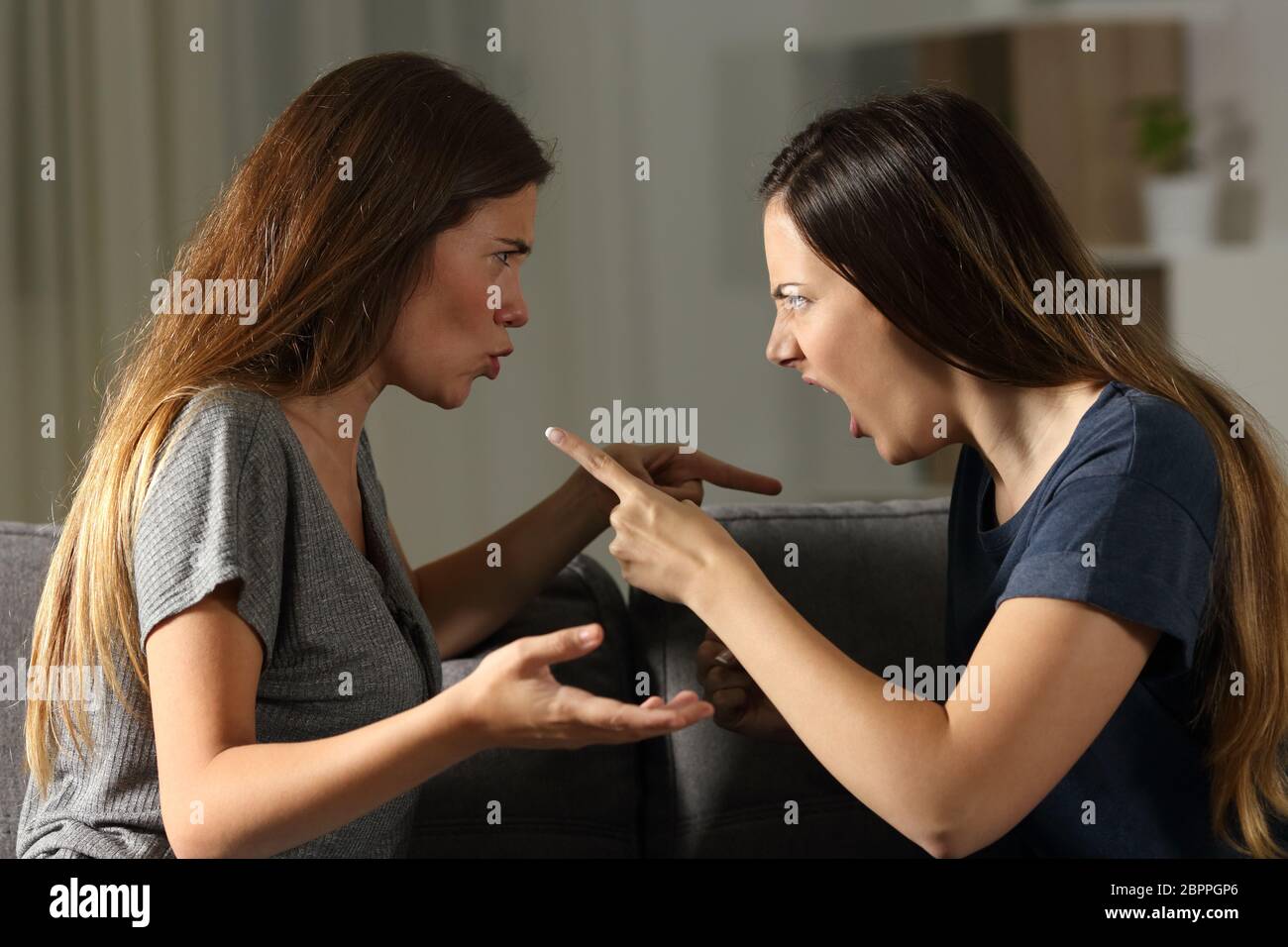 Side view portrait of two friends arguing and shouting in the night at ...