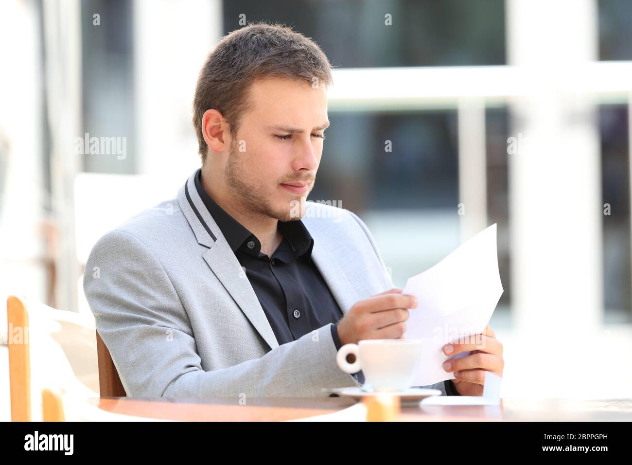 Serious executive reading a letter sitting in a coffee shop Stock Photo ...