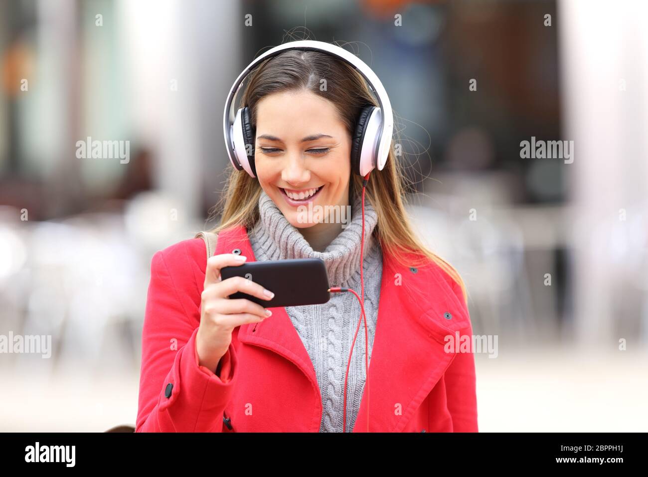 Front view of a happy girl watching videos on line in a smartphone or ...