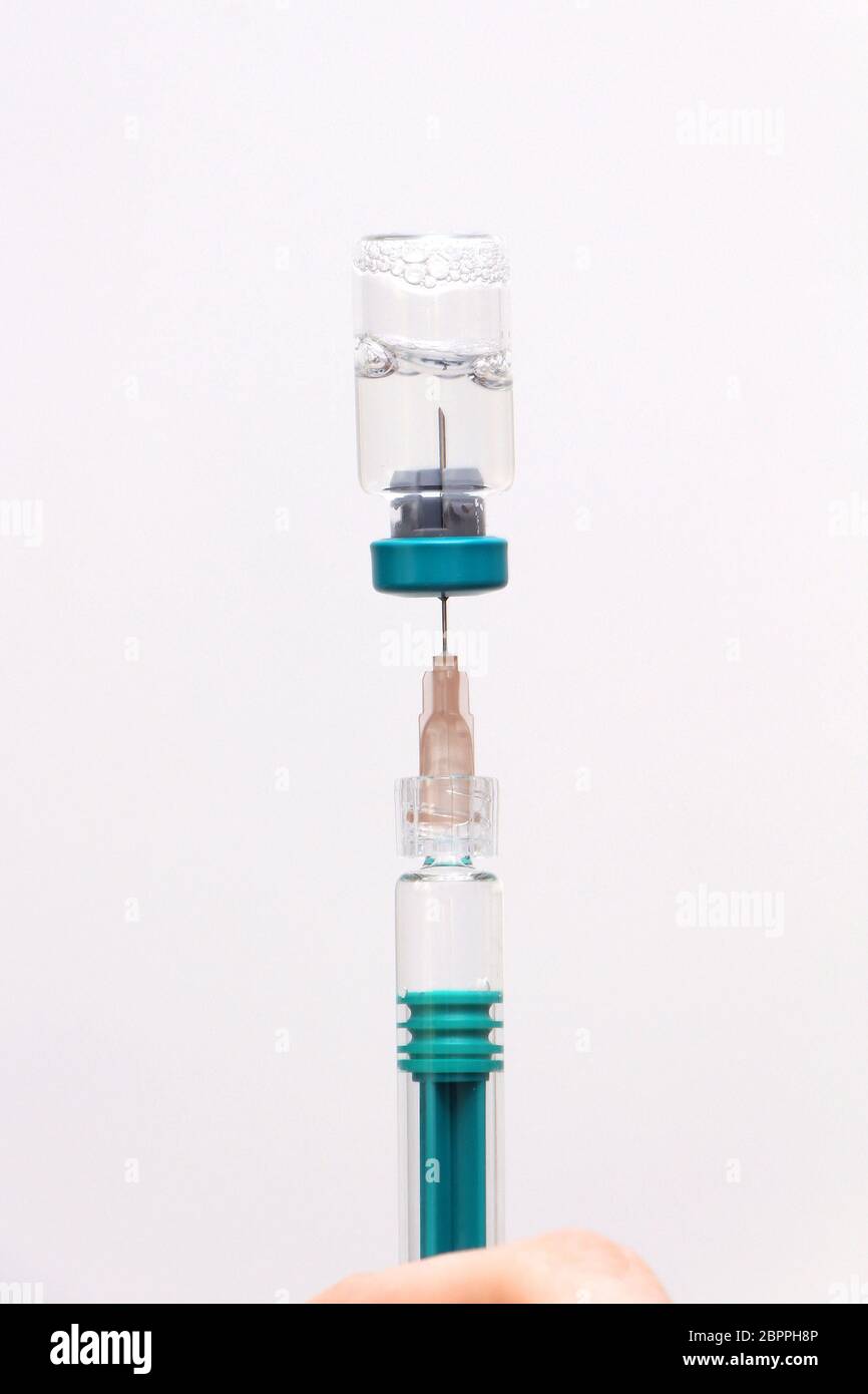 Human hand holding injection vial with needle inside on white ...