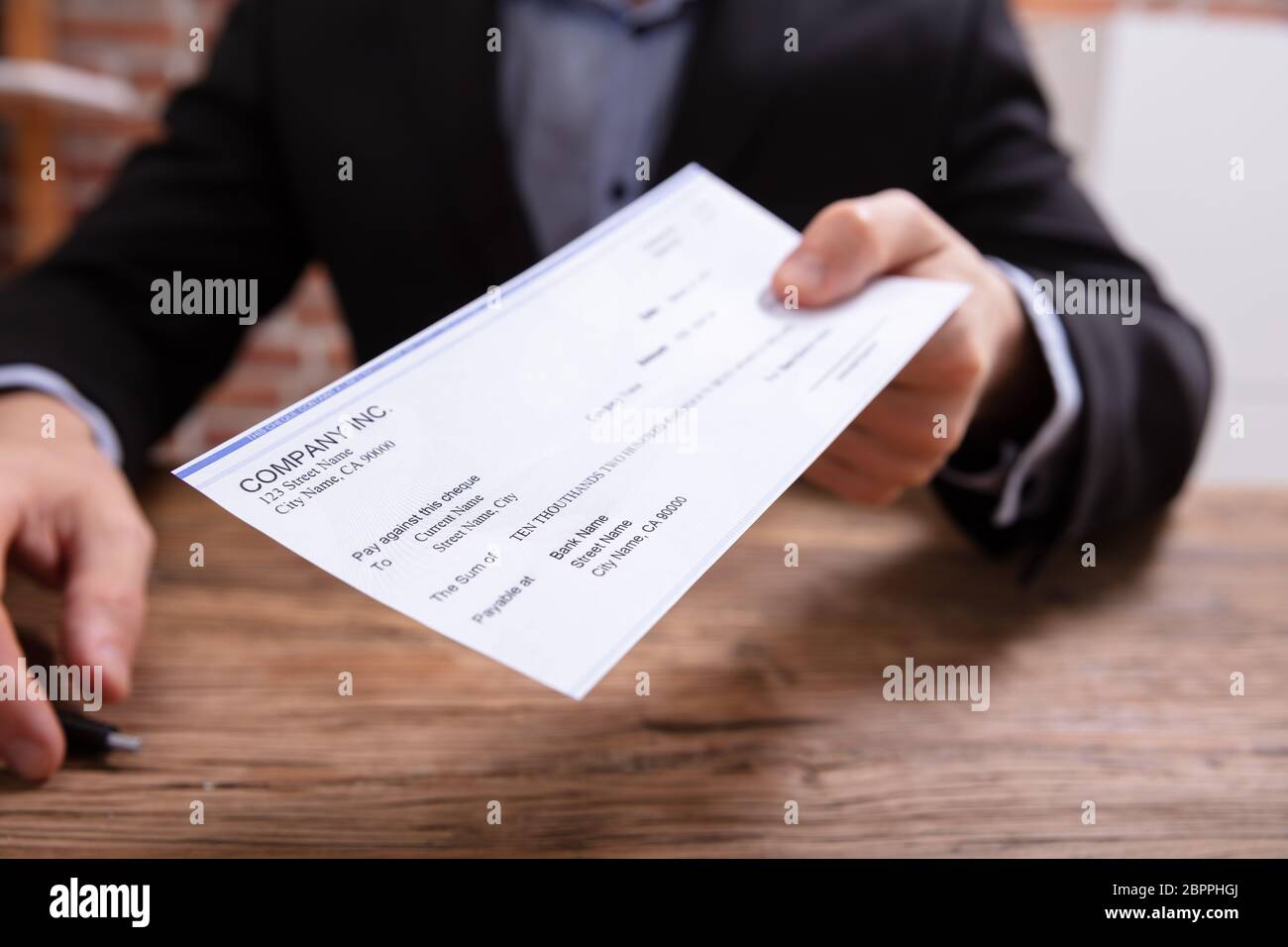 Mid-section Of Person Giving Cheque Over Wooden Desk Stock Photo - Alamy