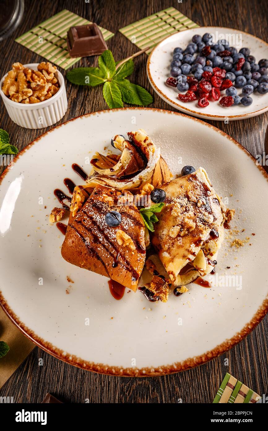 Crepes with chocolate cream decorated with chocolate syrup and walnuts ...