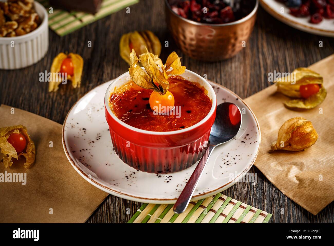 Delicious creme brulee served in red ramekin and decorated with cape ...