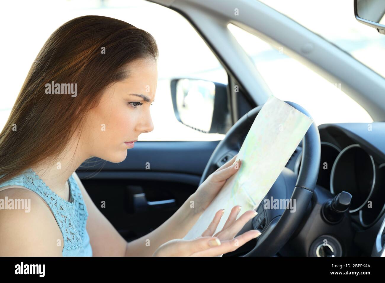 Side view portrait of a lost driver sitting inside her car trying to ...