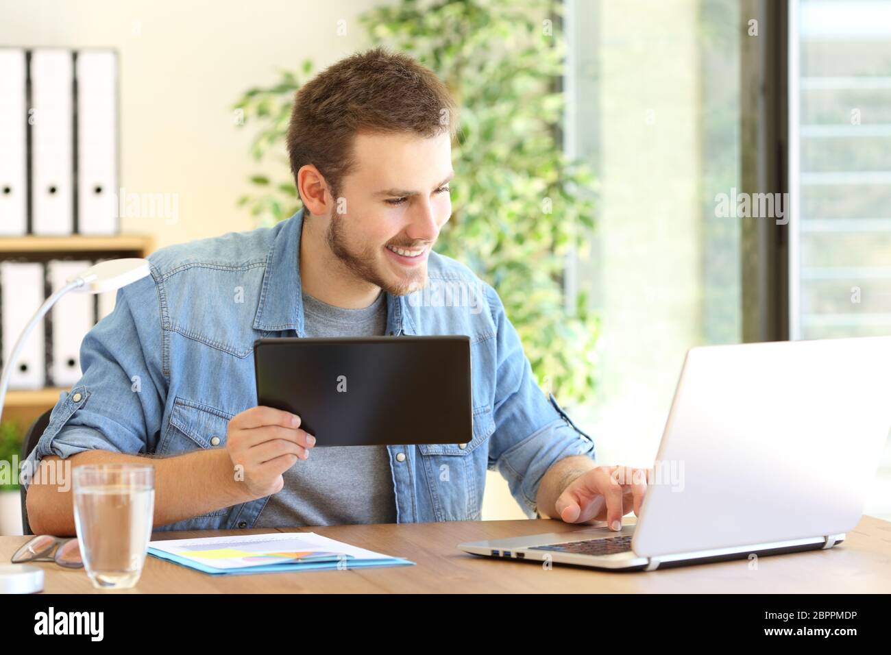 Entrepreneur working on line with a tablet and laptop in a desktop at ...