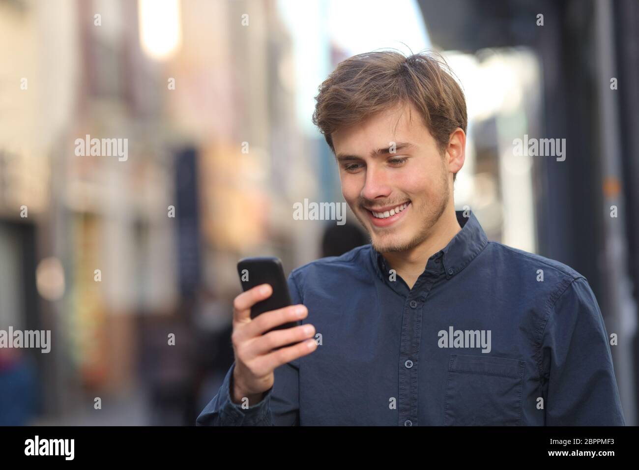 Happy man checking smart phone content walking in the street of an old ...