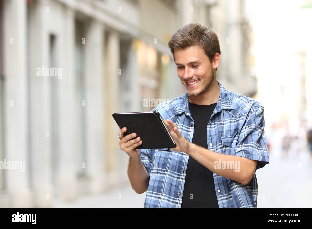 Happy man walking browsing tablet online content in the street Stock ...