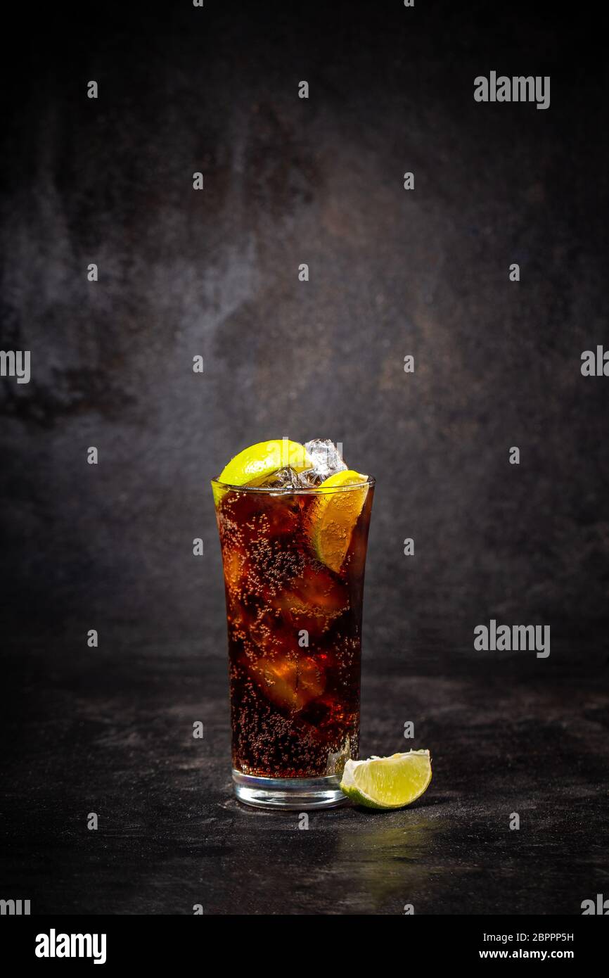 Glass of cuba libre decorated with lime on black background Stock Photo ...