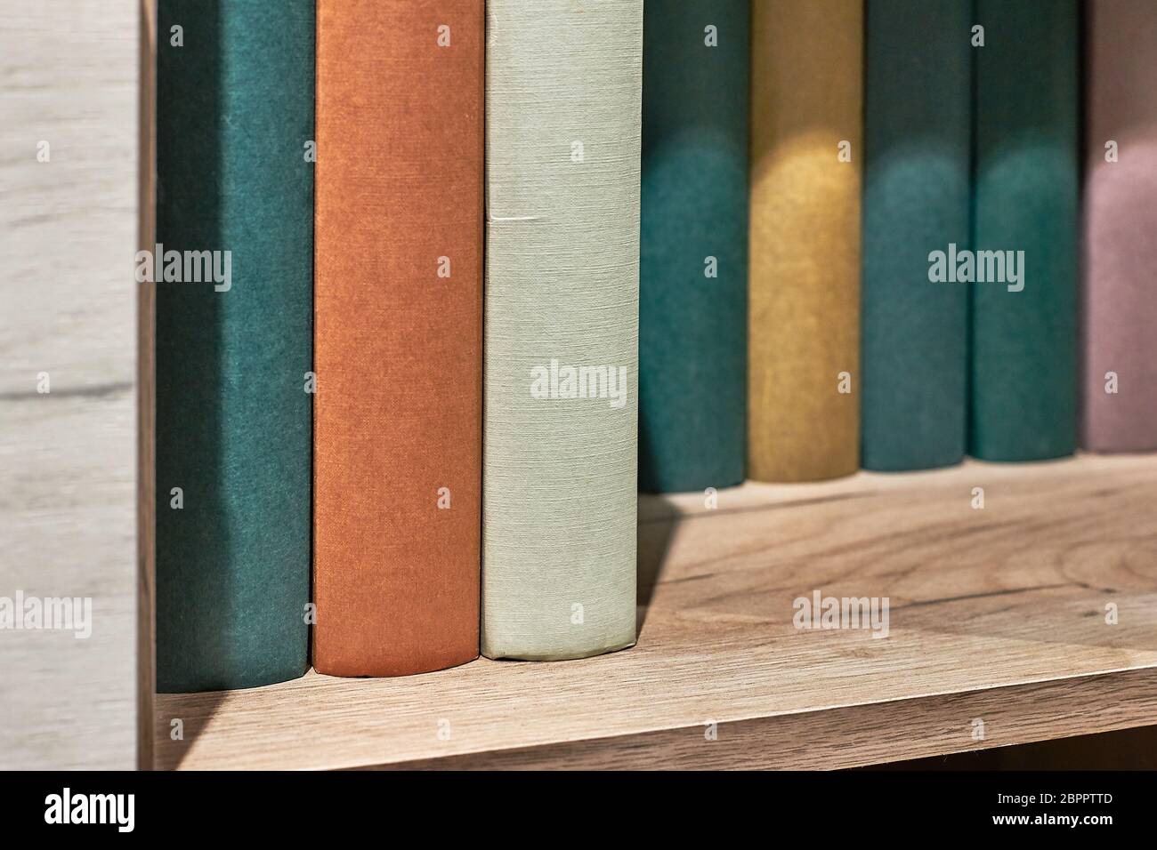 Wooden book shelf with series of books, no titles shown, blank sides ...