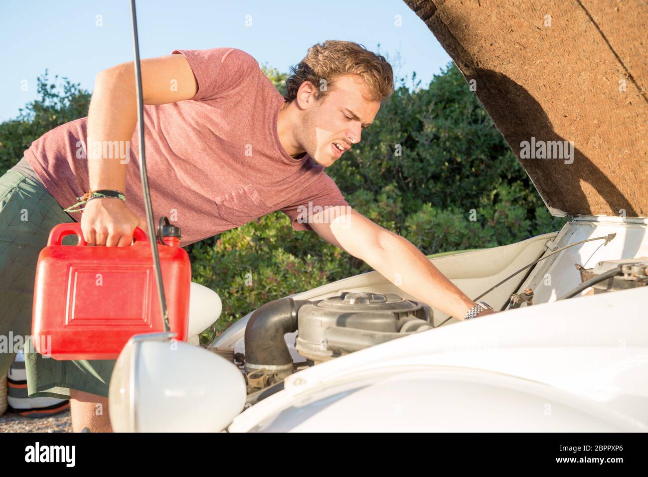 Young man looking at the engine of a broken car Stock Photo - Alamy