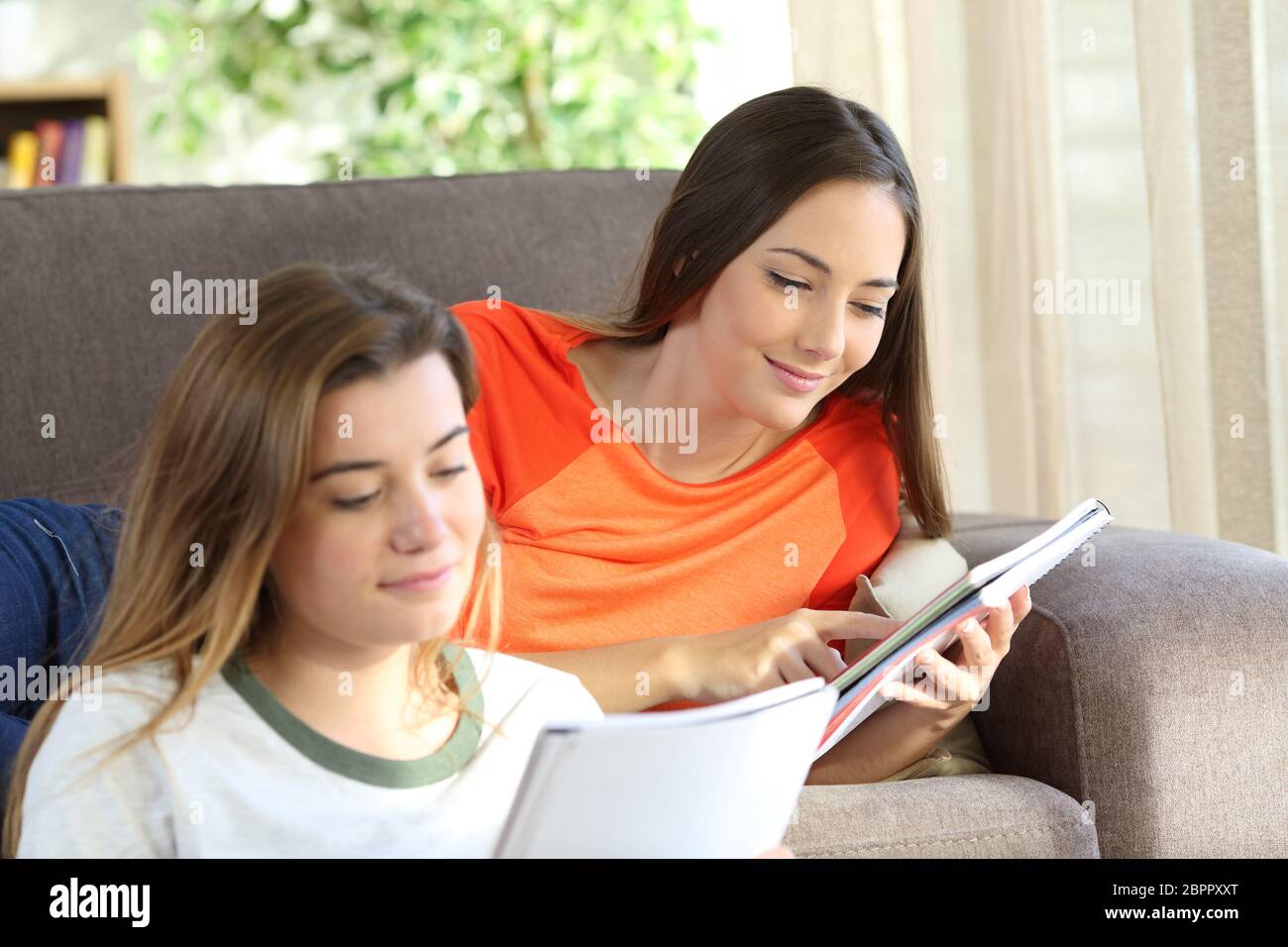 Two concentrated students learning reading notebooks on a couch in the ...