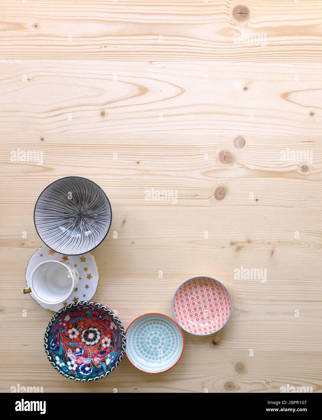 different kinds of modern colourful crockery on light wood background ...