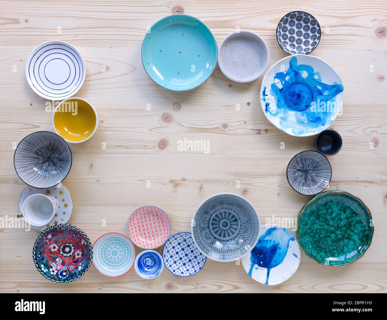 different kinds of modern colourful crockery on light wood background ...