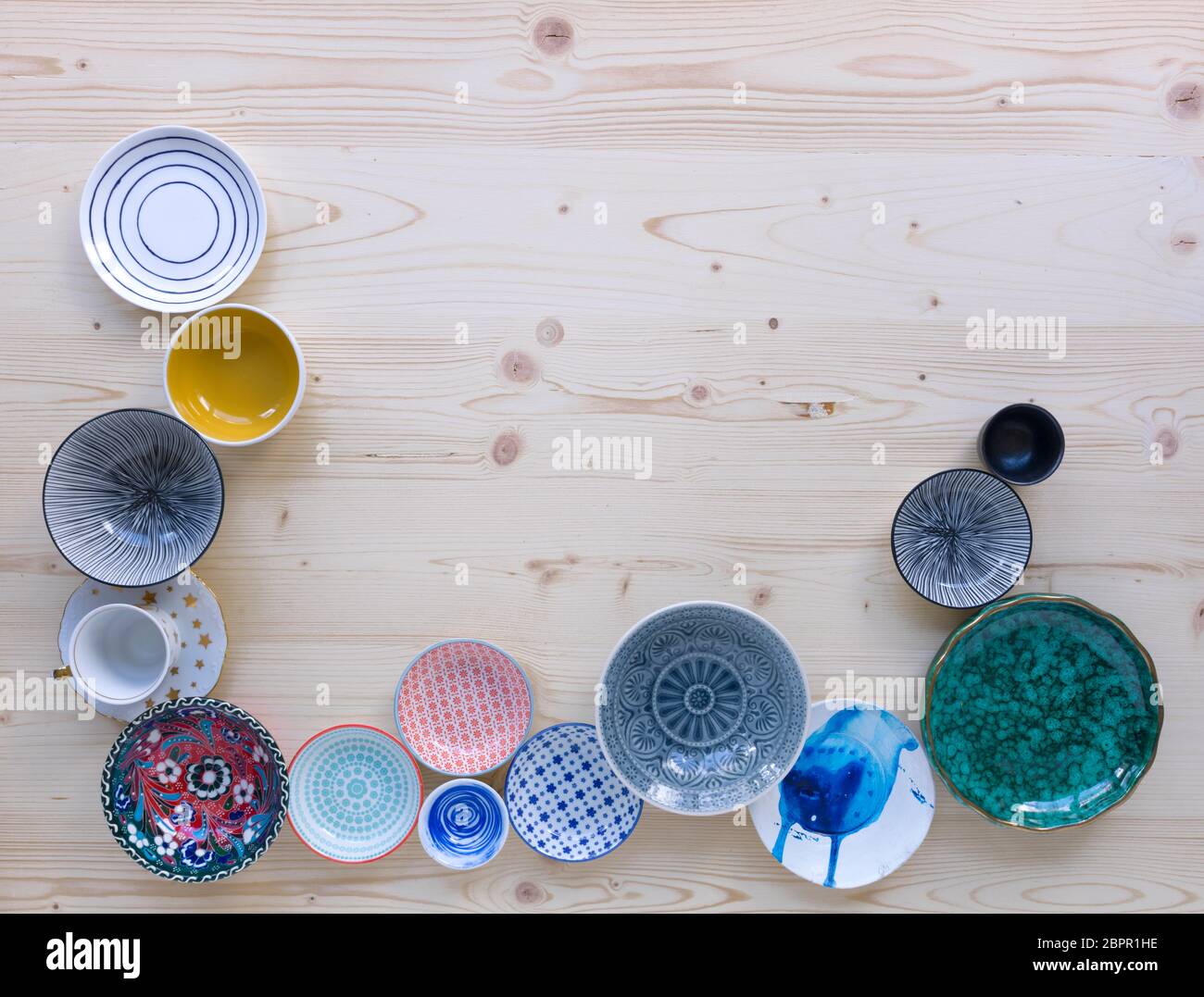 different kinds of modern colourful crockery on light wood background ...