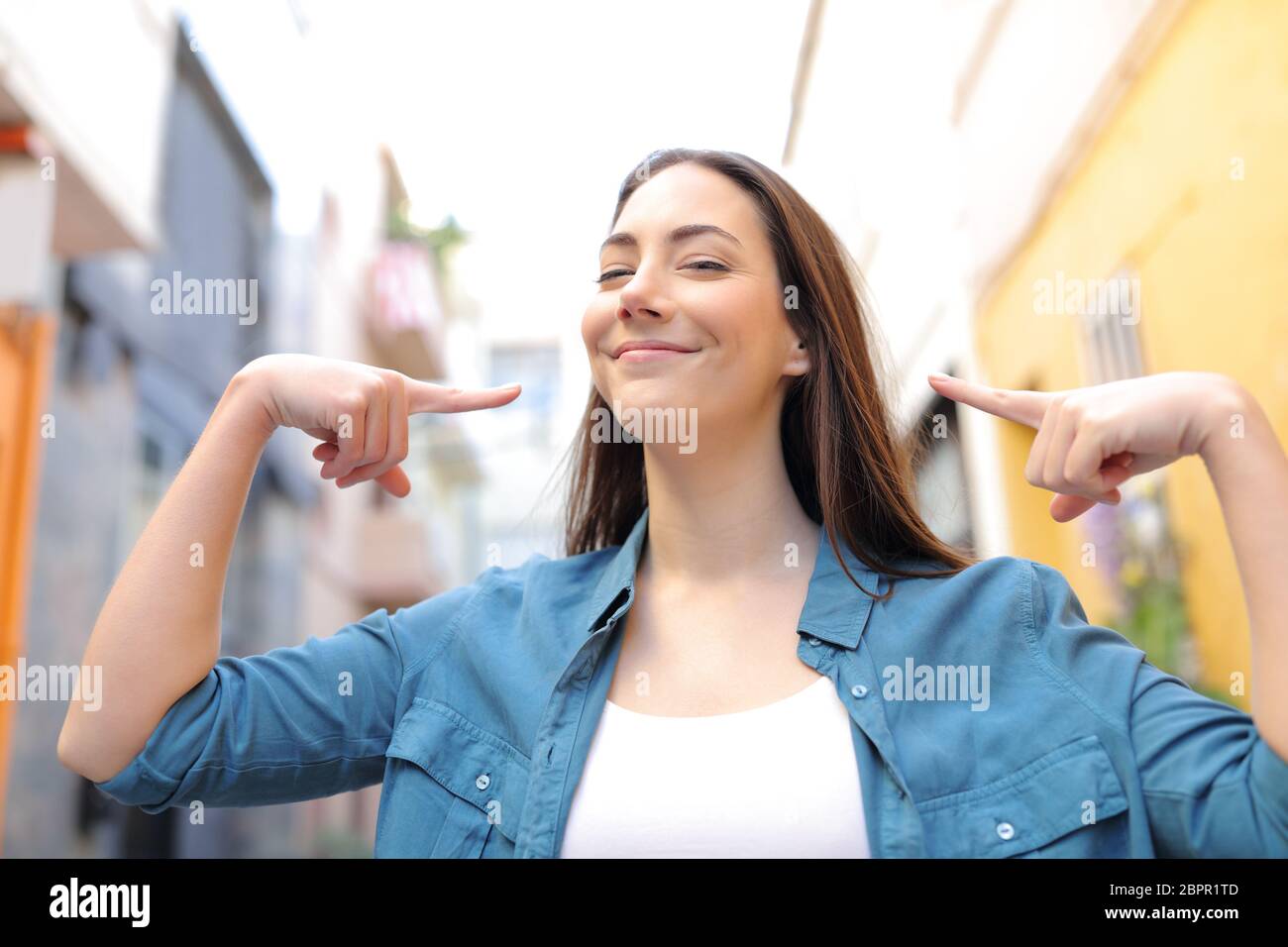 Front view portrait of a proud woman pointing herself in the street ...