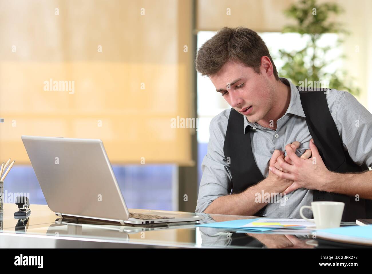 Businessman suffering a heart attack with his hands grabbing the chest ...