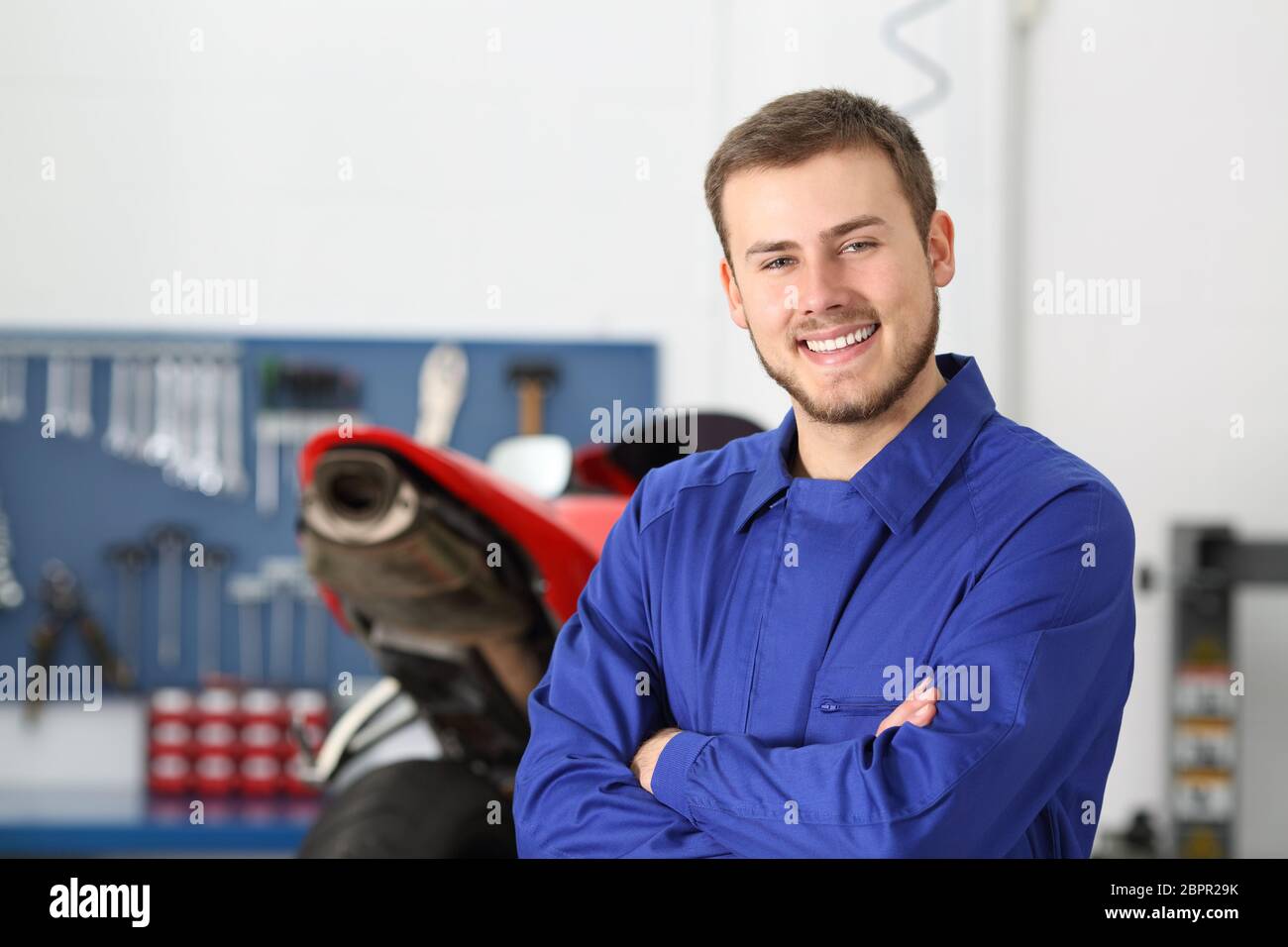 Front view portrait of a motorcycle mechanic posing standing looking at ...