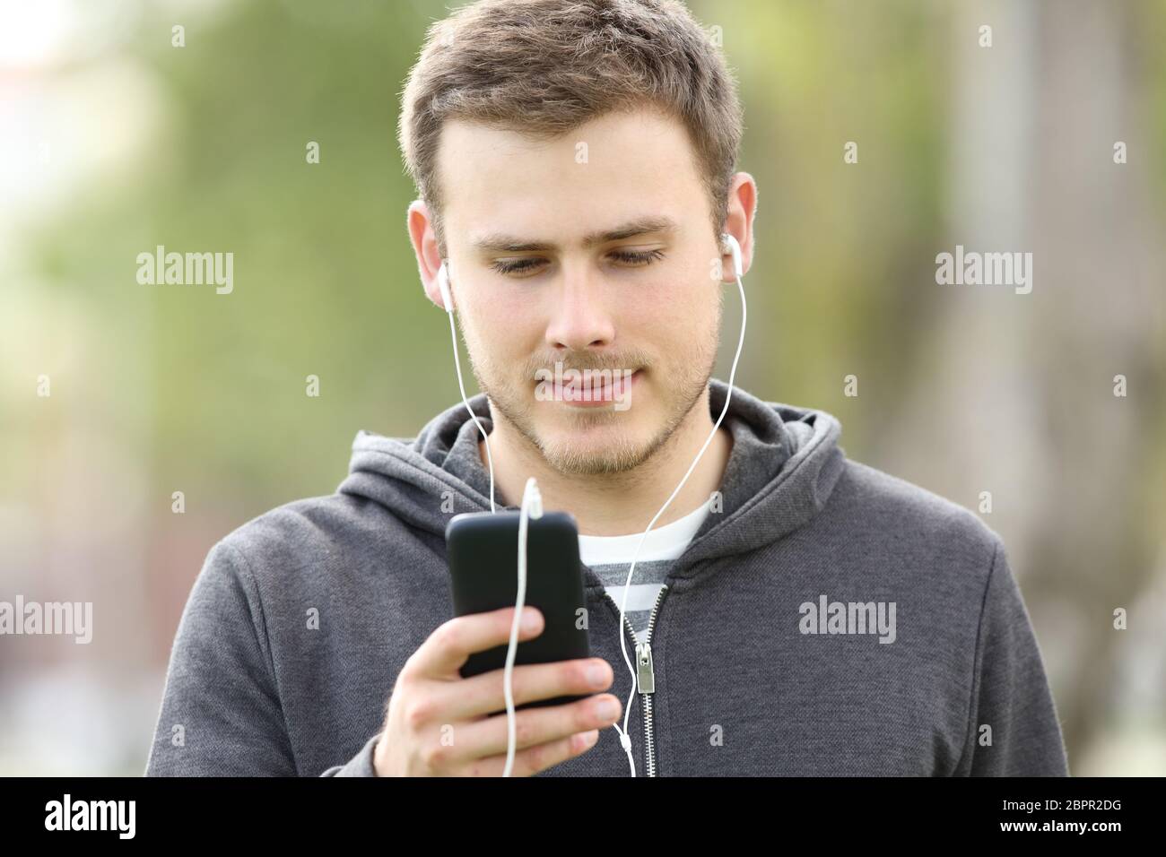 Front view portrait of a teen listening music on line with earbuds and ...