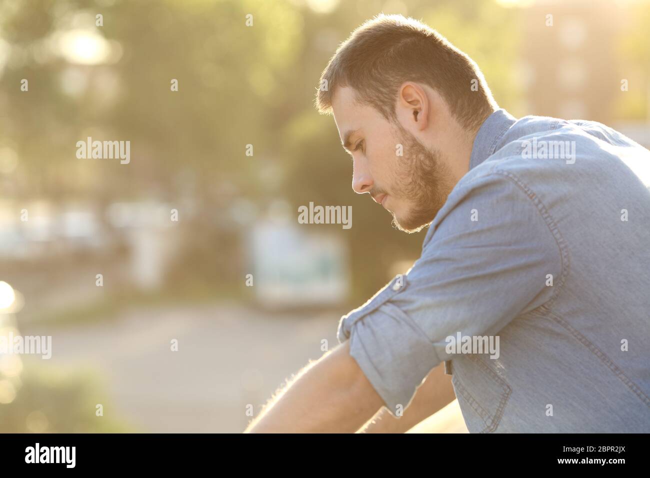Side view of one sad man looking down in a balcony Stock Photo - Alamy