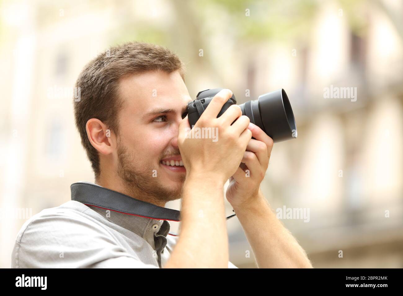 Side view of a happy man photographing with a dslr camera in the street ...