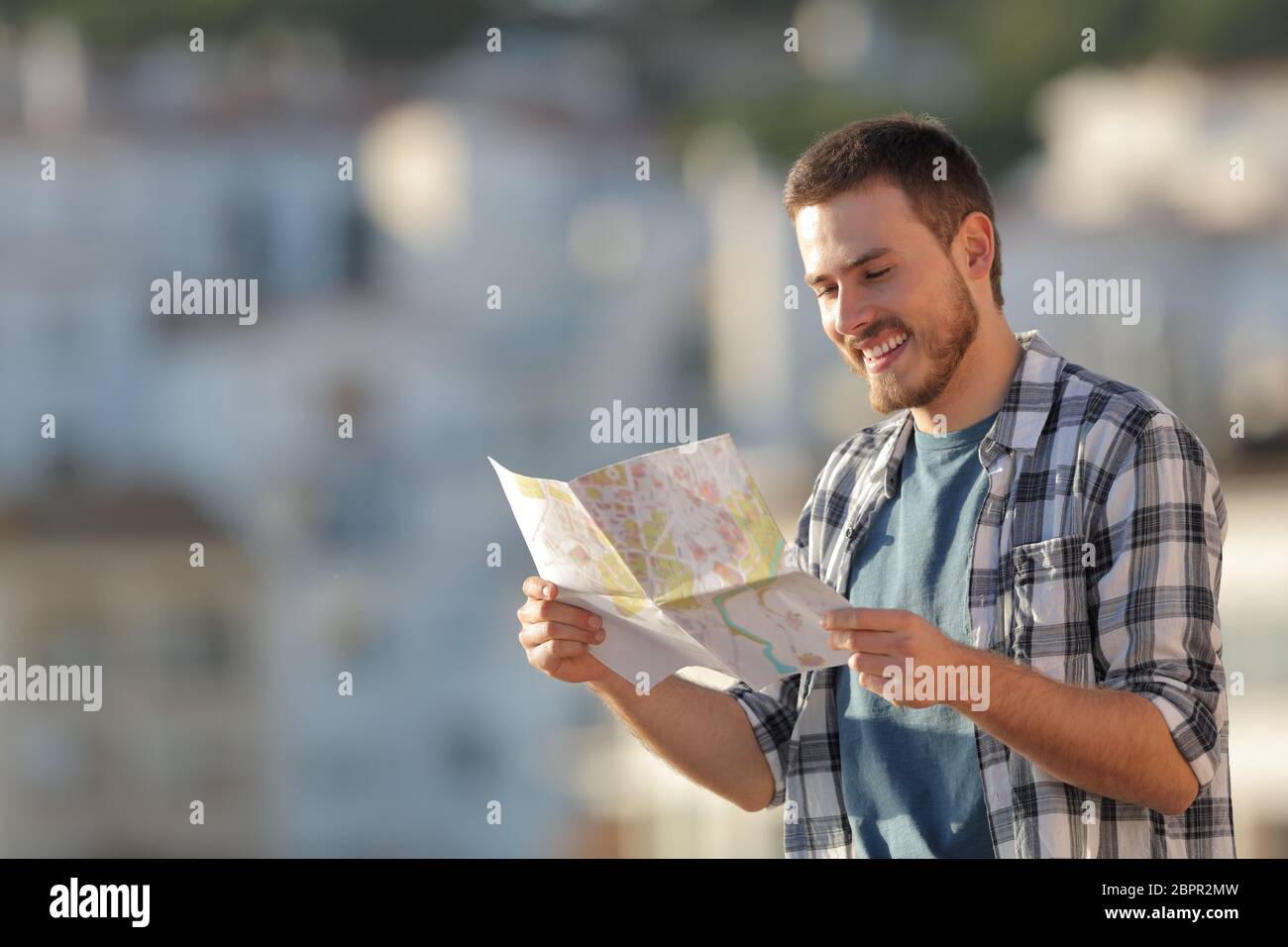 Happy tourist checking paper map in a town on vacation Stock Photo - Alamy