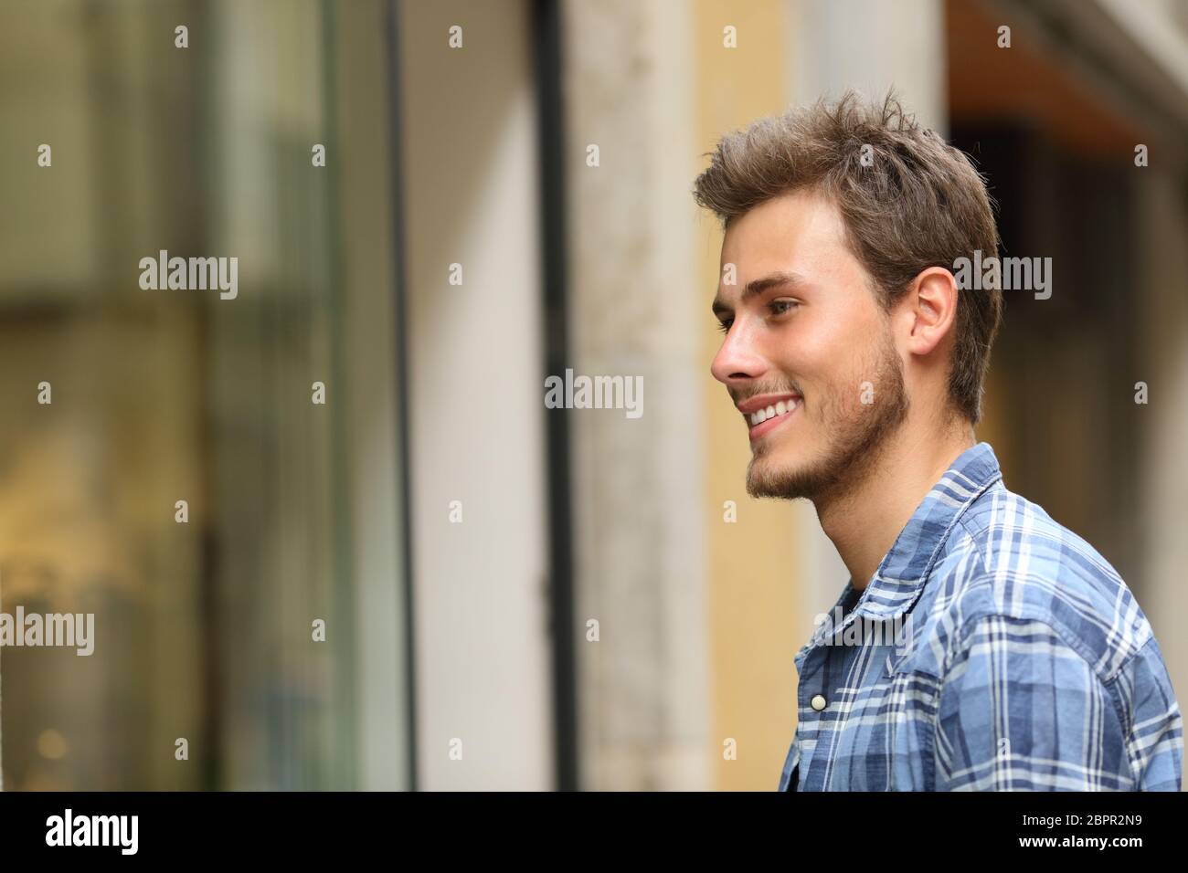 Side view portrait of a happy man watching storefront in the street ...