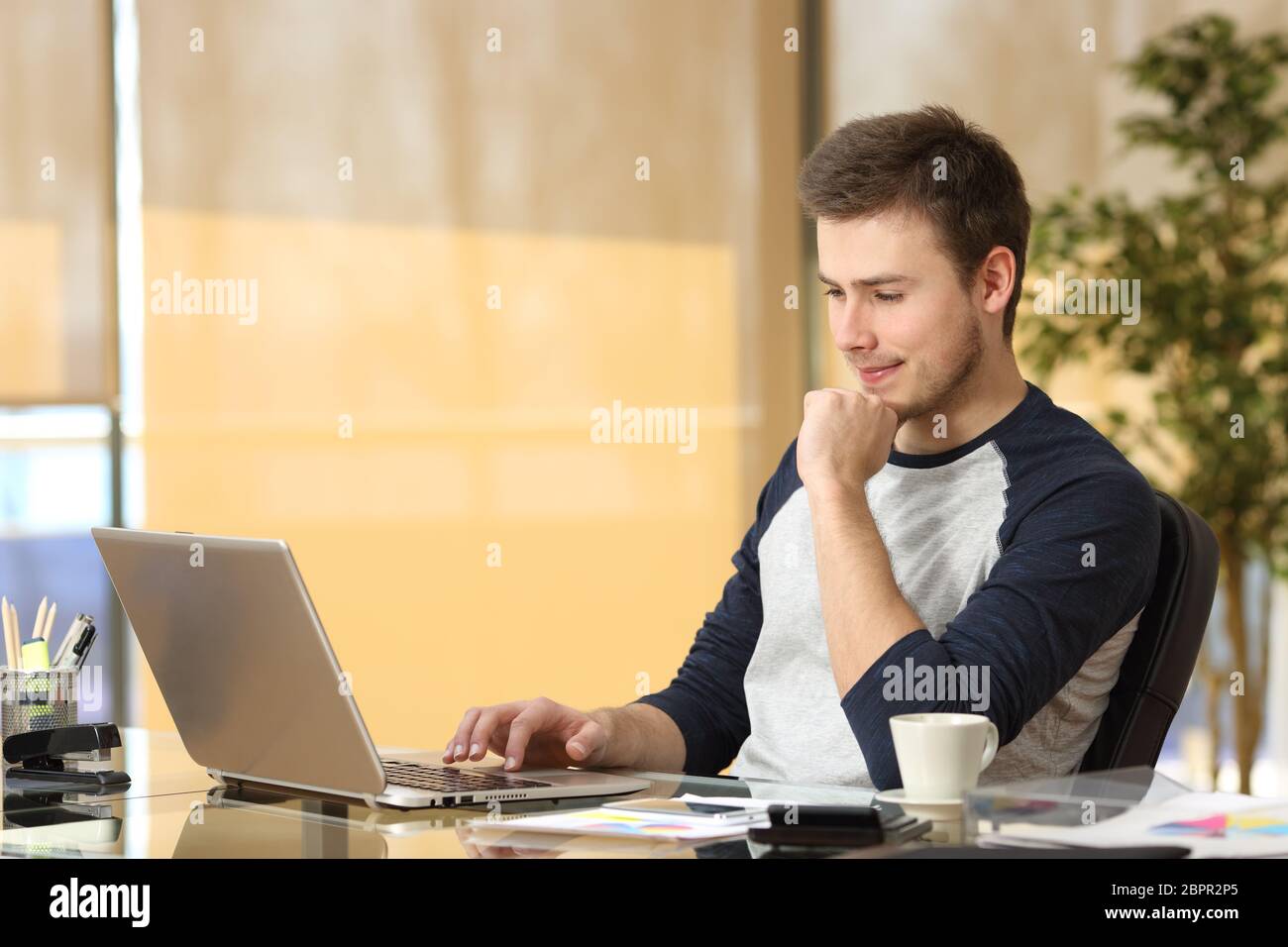 Young entrepreneur working on line with a laptop in a desktop at office ...
