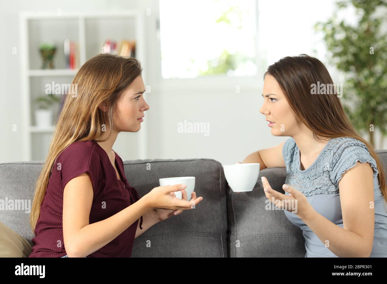 Two friends talking seriously sitting on a couch at home Stock Photo ...