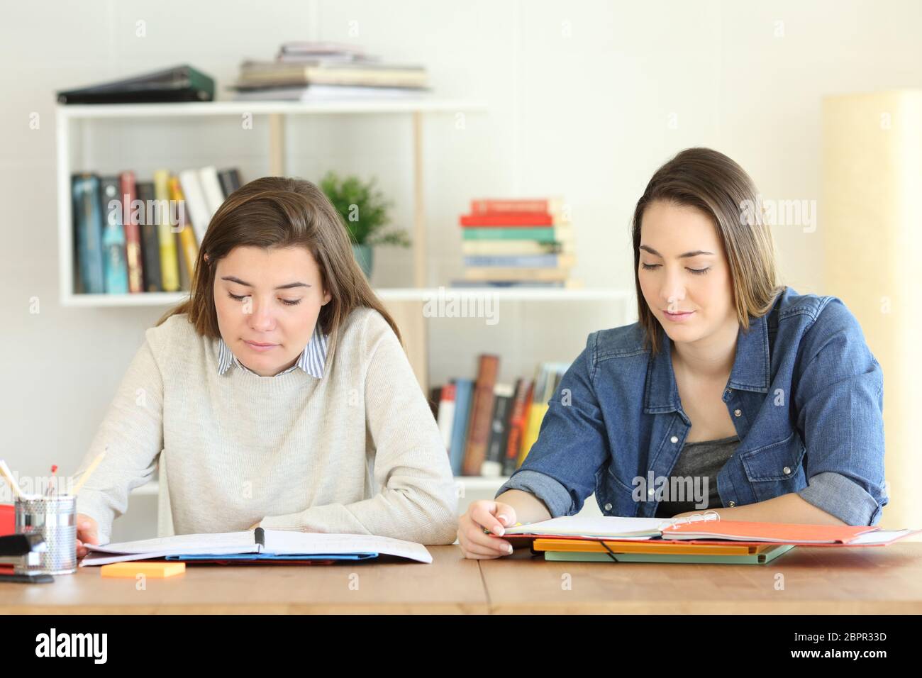 Two students studying together reading notes on a table at home Stock ...