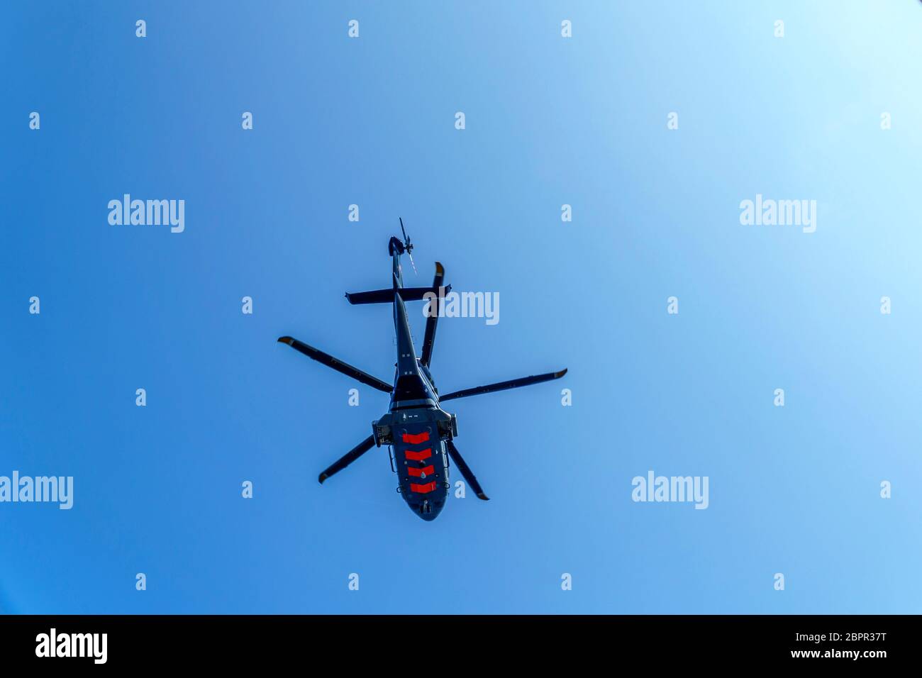 Low angle commercial helicopter take off from helipad with blue sky ...