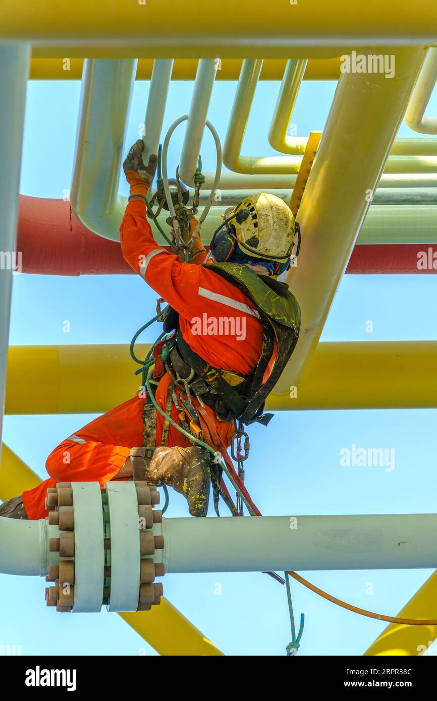 Working at height. An abseiler from rear view with dirty coverall ...