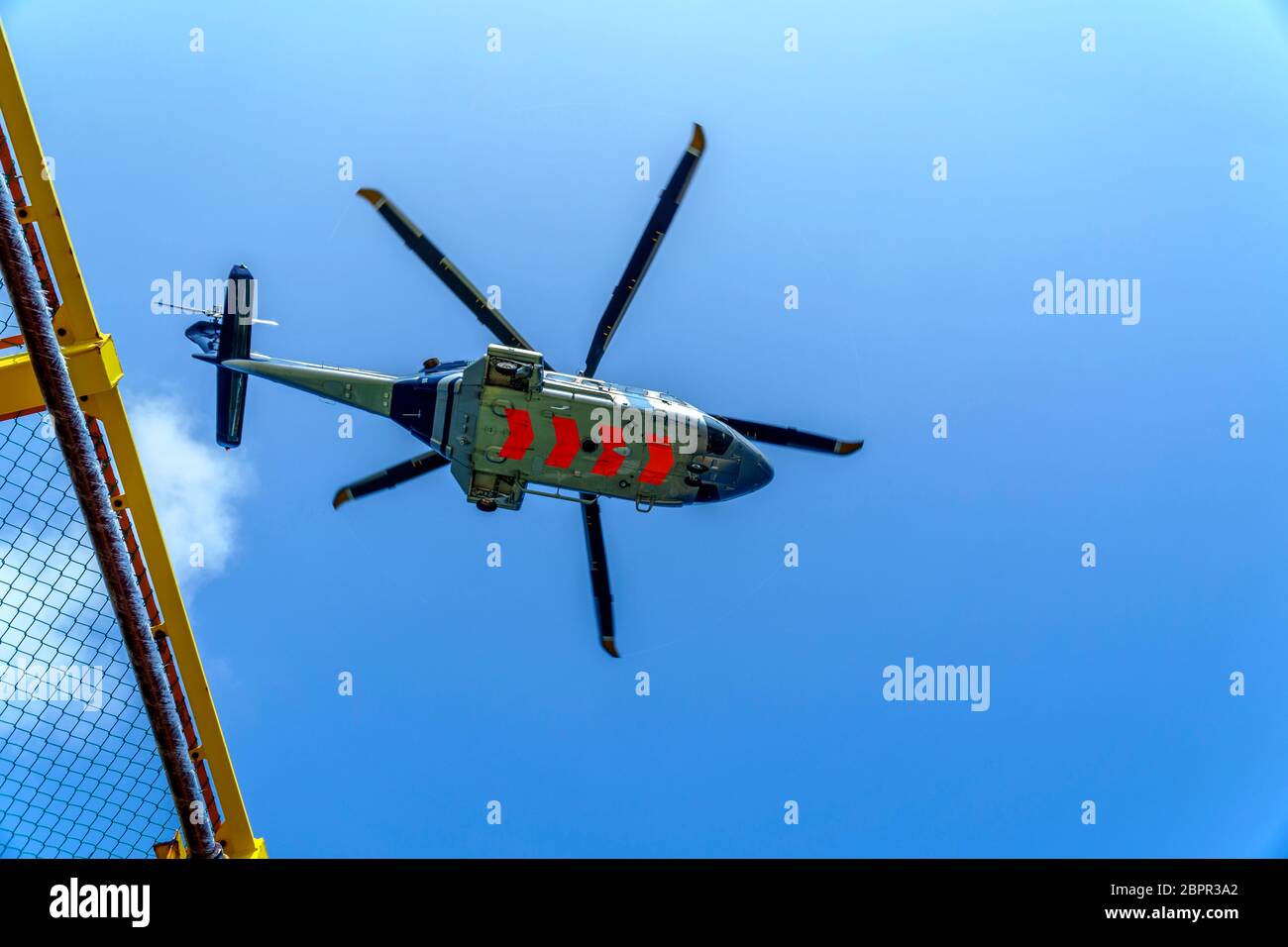 Low angle commercial helicopter take off from helipad with blue sky ...
