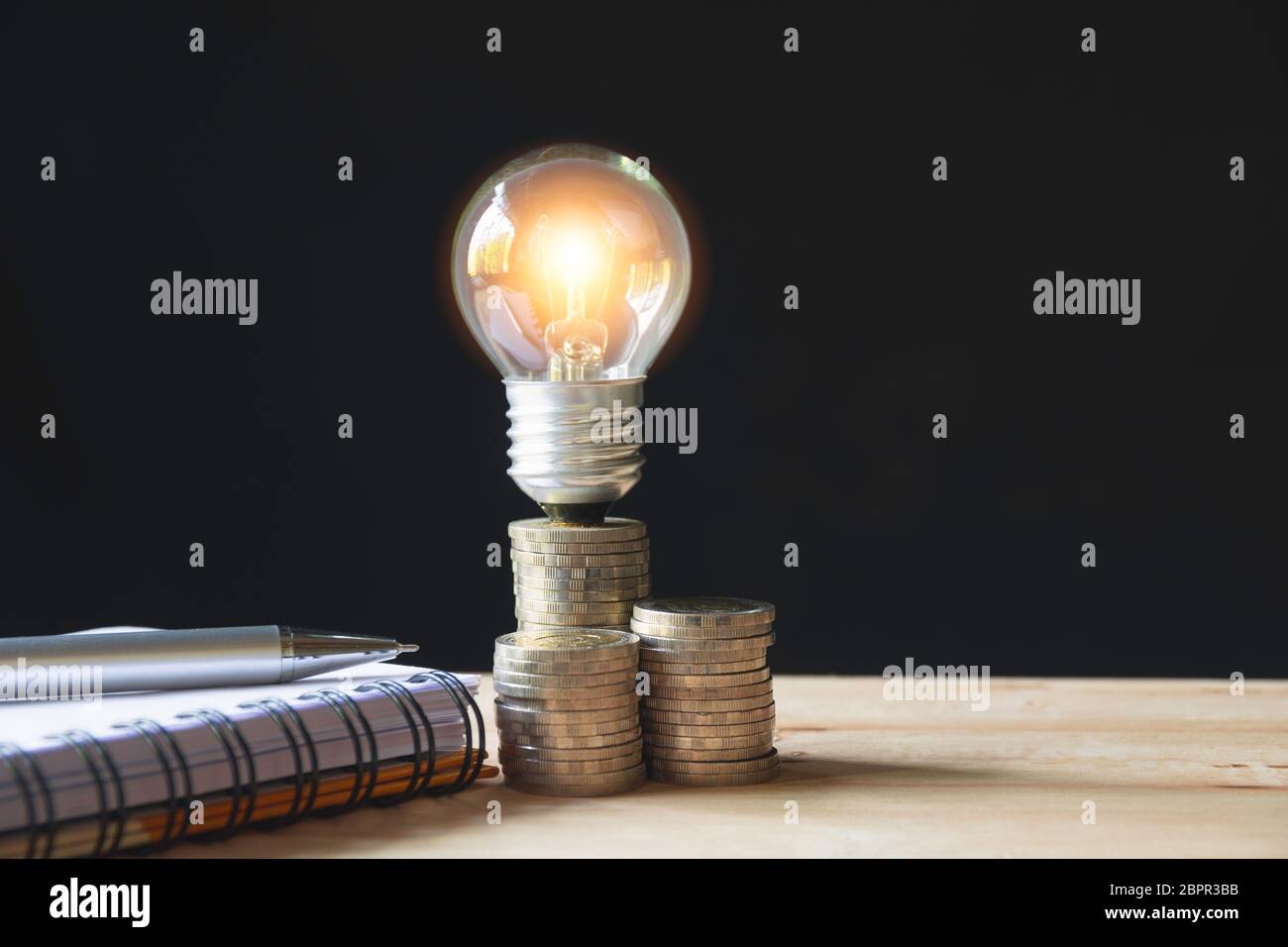 A light bulb on stack of coins for business and accounting concept ...