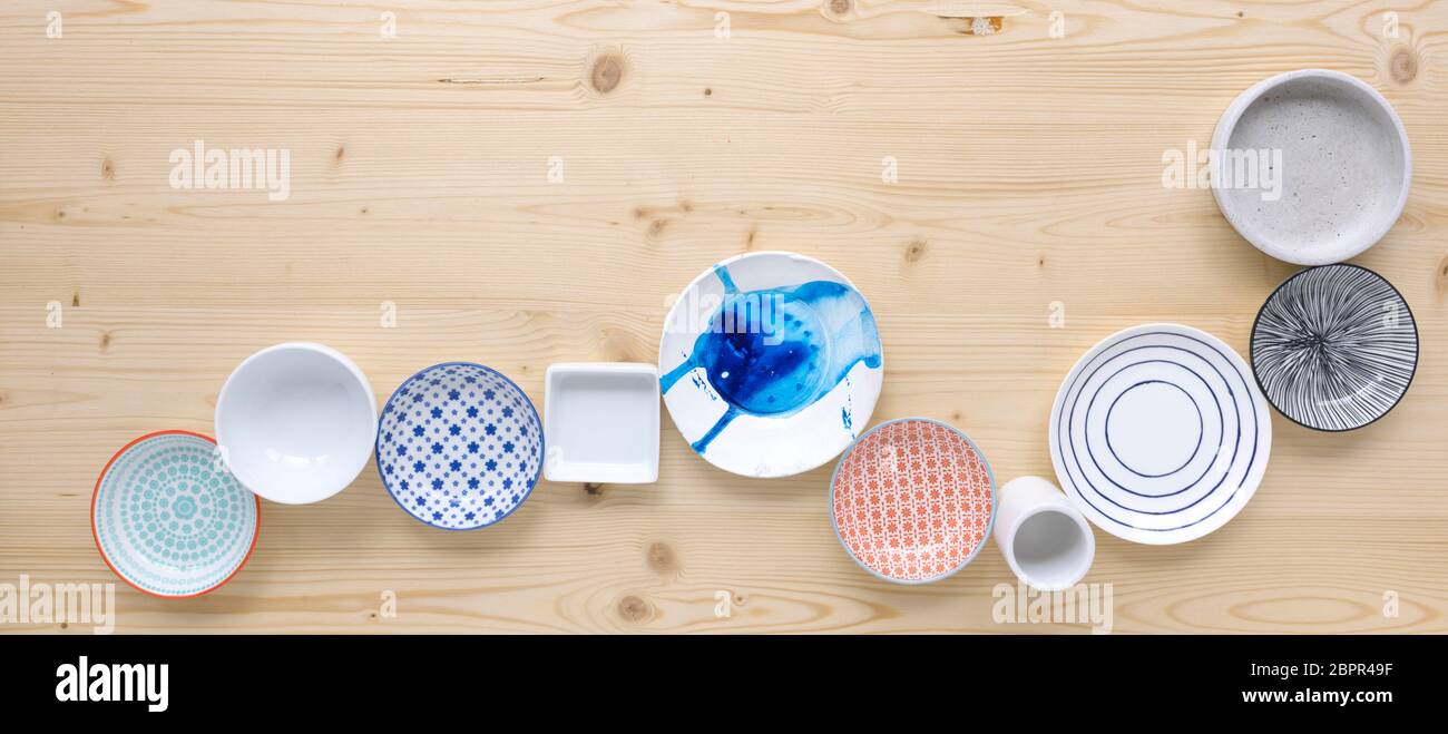 different kinds of modern colourful and white crockery on light wood ...