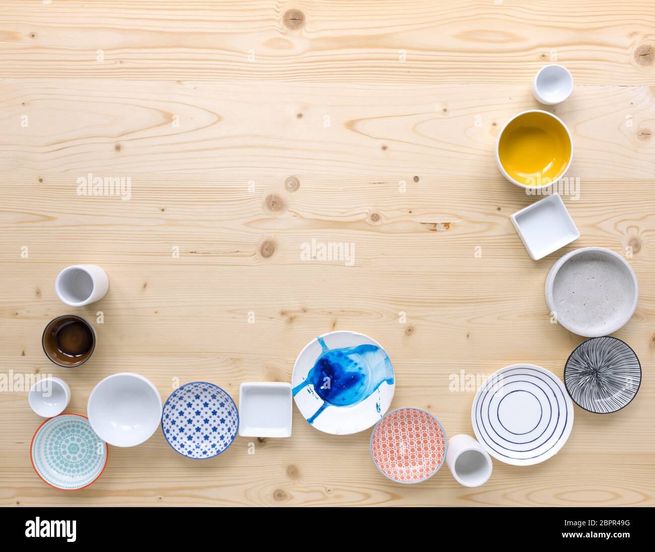 different kinds of modern colourful and white crockery on light wood ...