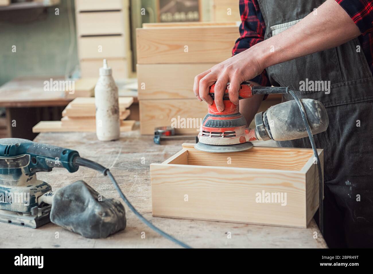 Worker grinds the wood box of angular grinding machine Stock Photo - Alamy
