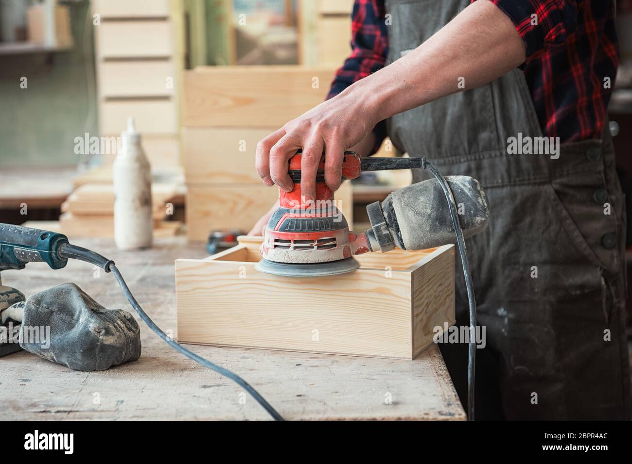 Worker grinds the wood box of angular grinding machine Stock Photo - Alamy