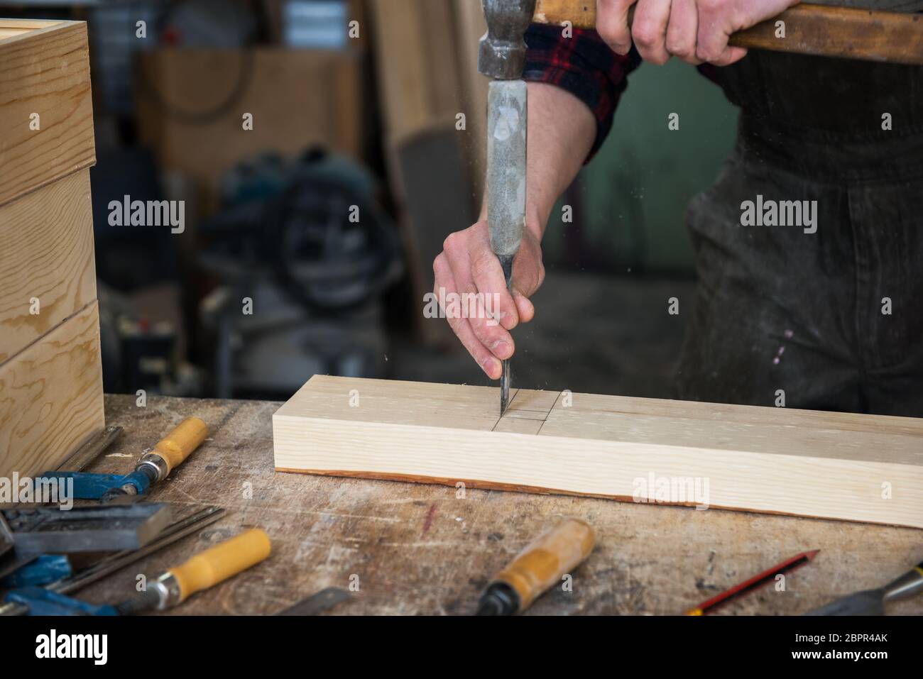 Carpenter working with a chisel and hammer in a wooden workshop ...