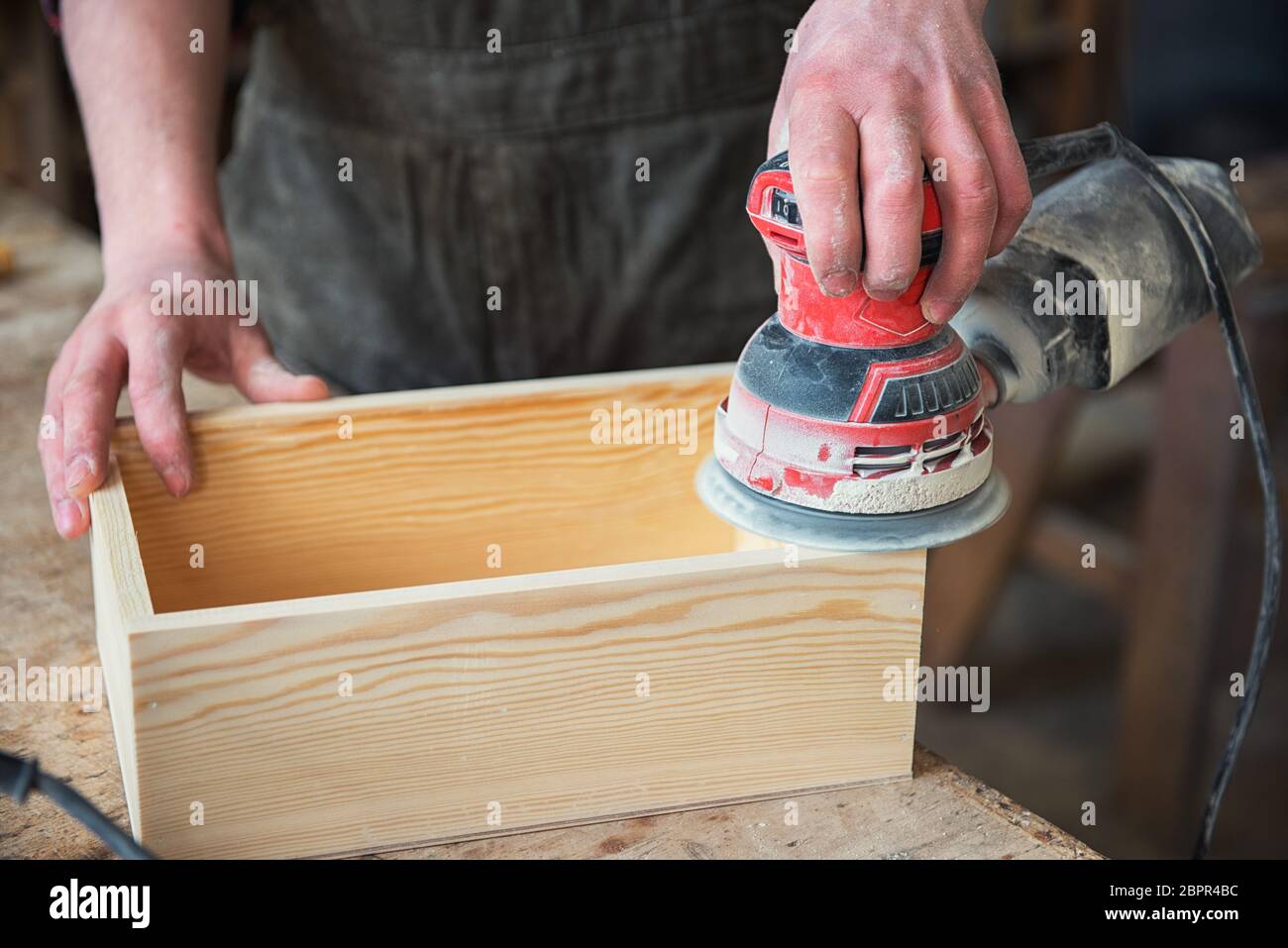 Worker grinds the wood box of angular grinding machine. Profession ...