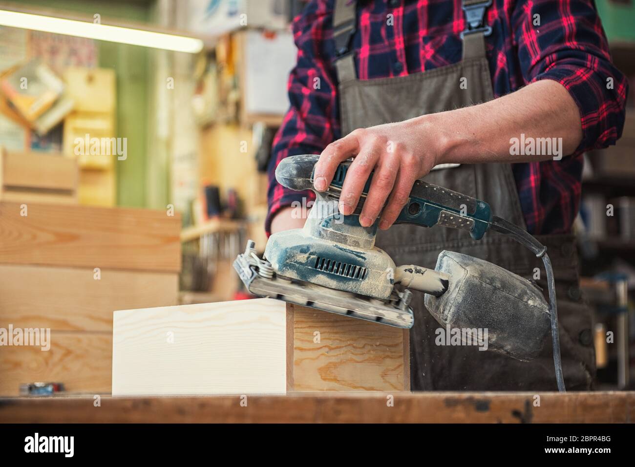 Worker grinds the wood box of angular grinding machine. Profession ...