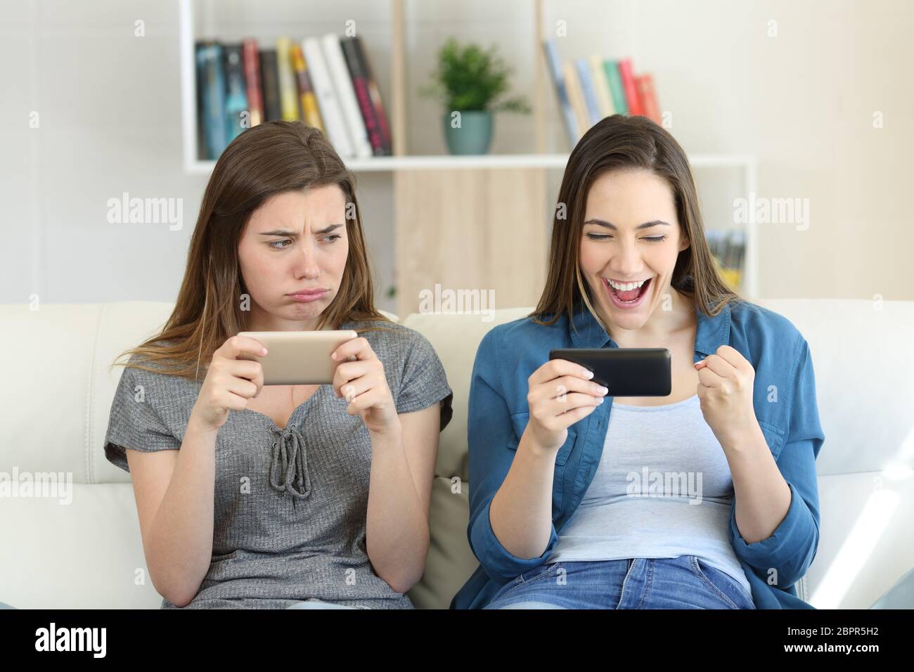 Front view portrait of a envious loser girl looking at her winner ...