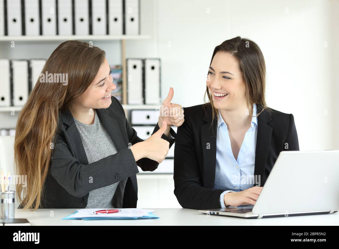 Office worker congratulating her colleague for a good job Stock Photo ...