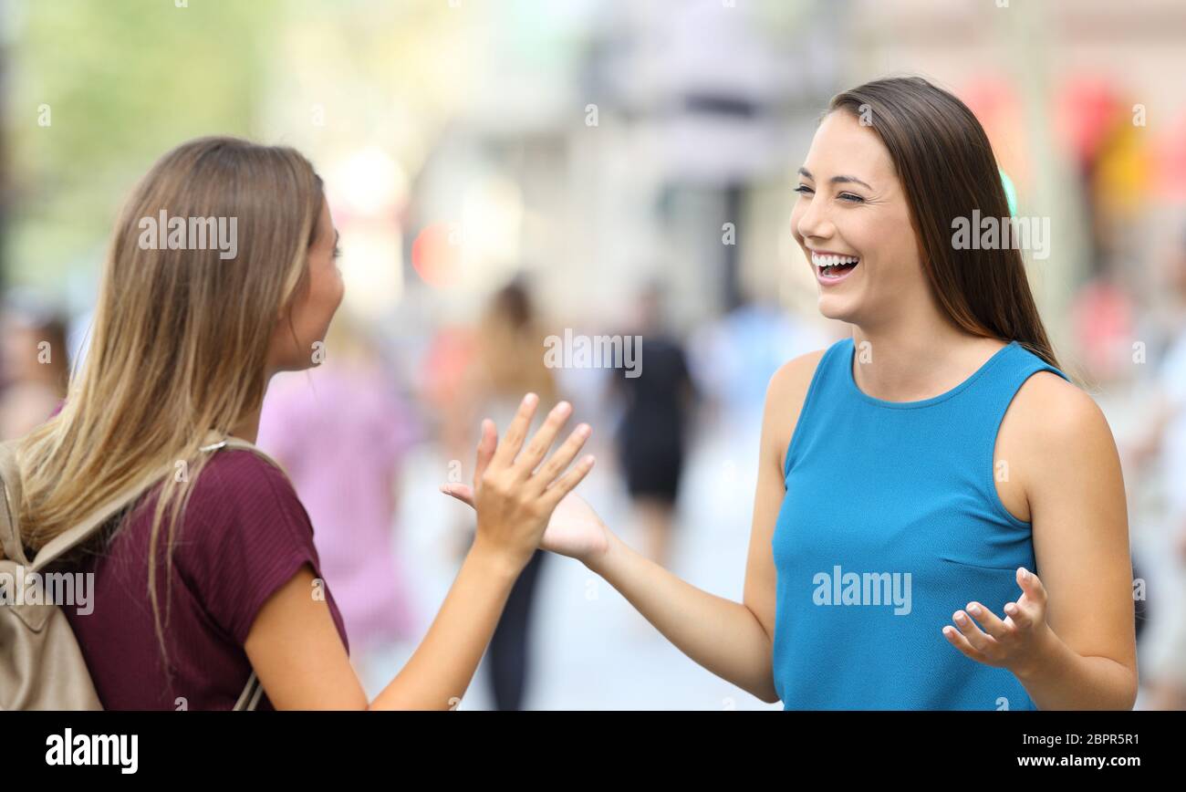 Two happy friends greeting and meeting on the street Stock Photo - Alamy