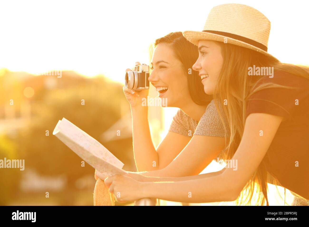 Two tourists photographing with a vintage camera from an hotel balcony ...