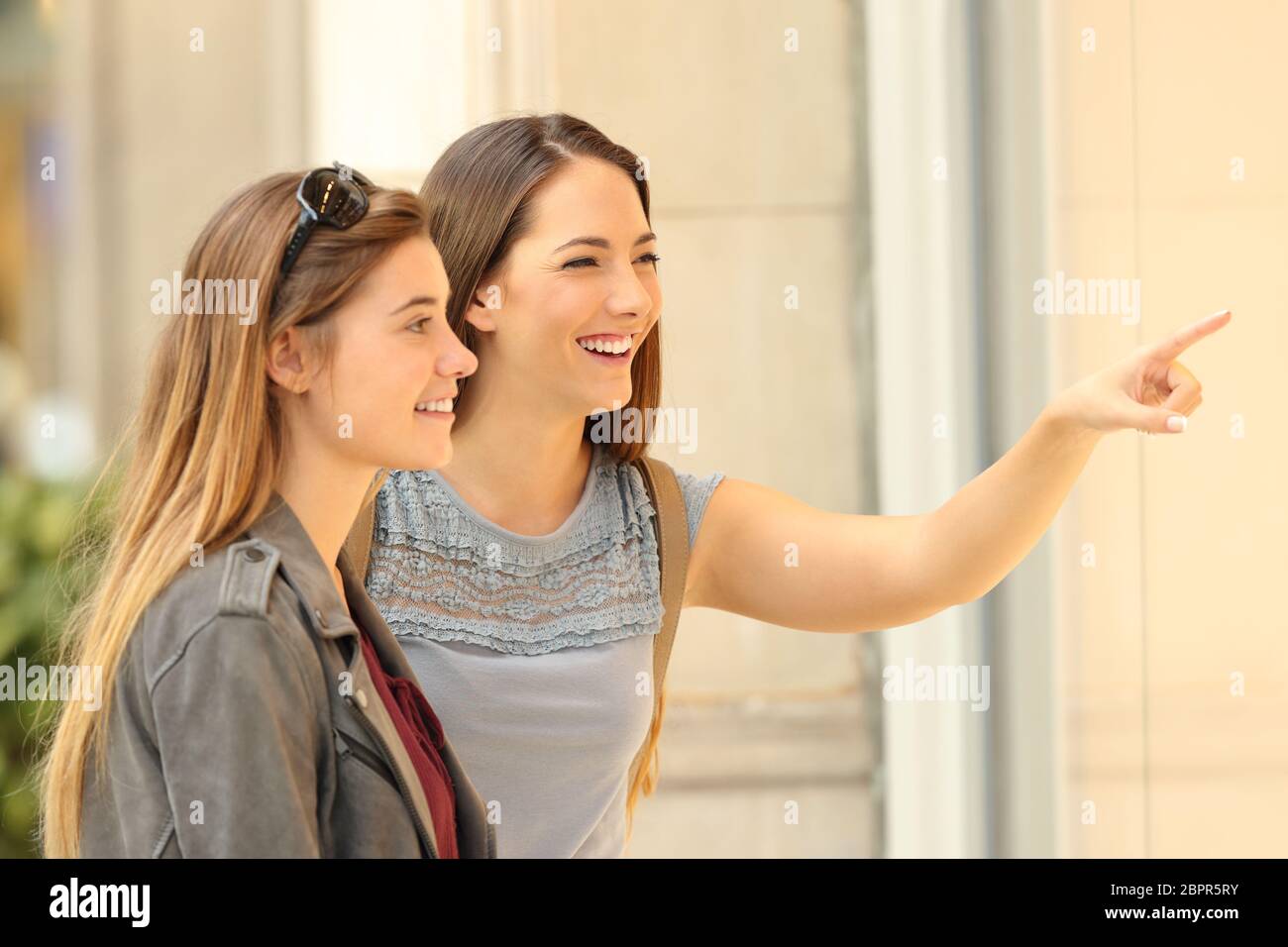 Two happy shoppers watching a storefront on the street Stock Photo - Alamy
